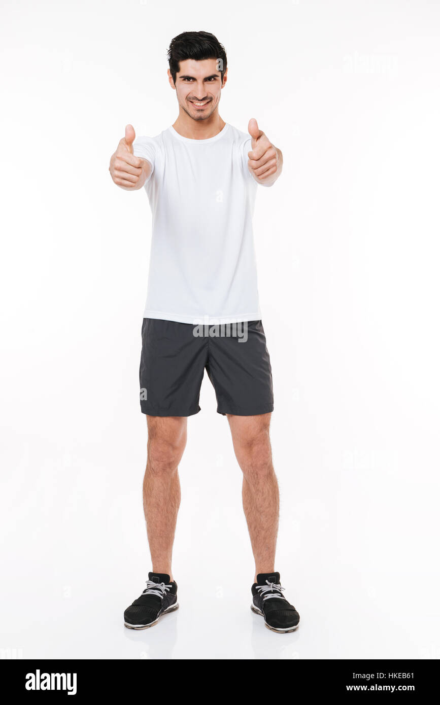Full length portrait of a happy fitness man showing two thumbs up ...