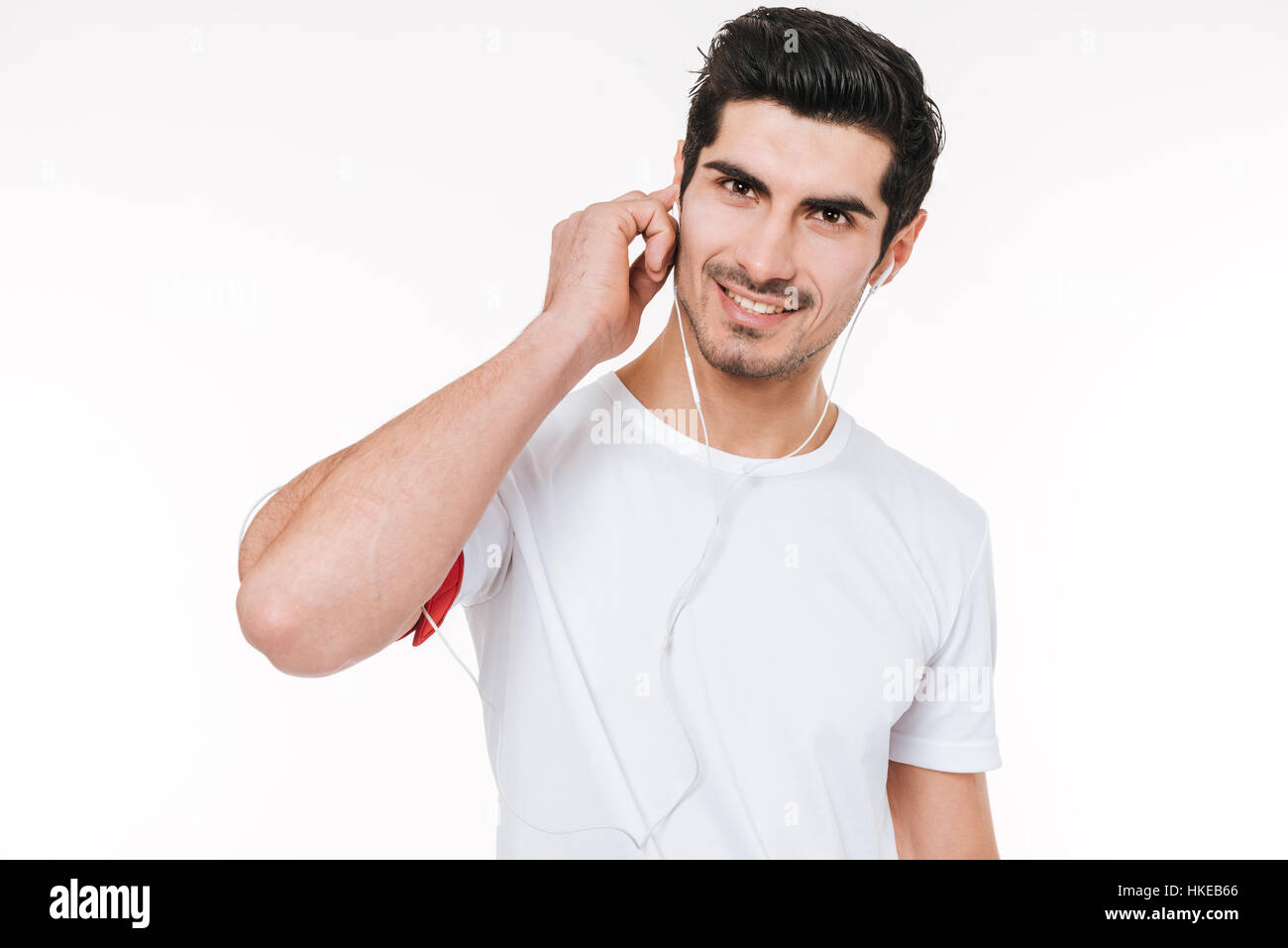 Close up portrait of smiling young male athlete listening to music with ...