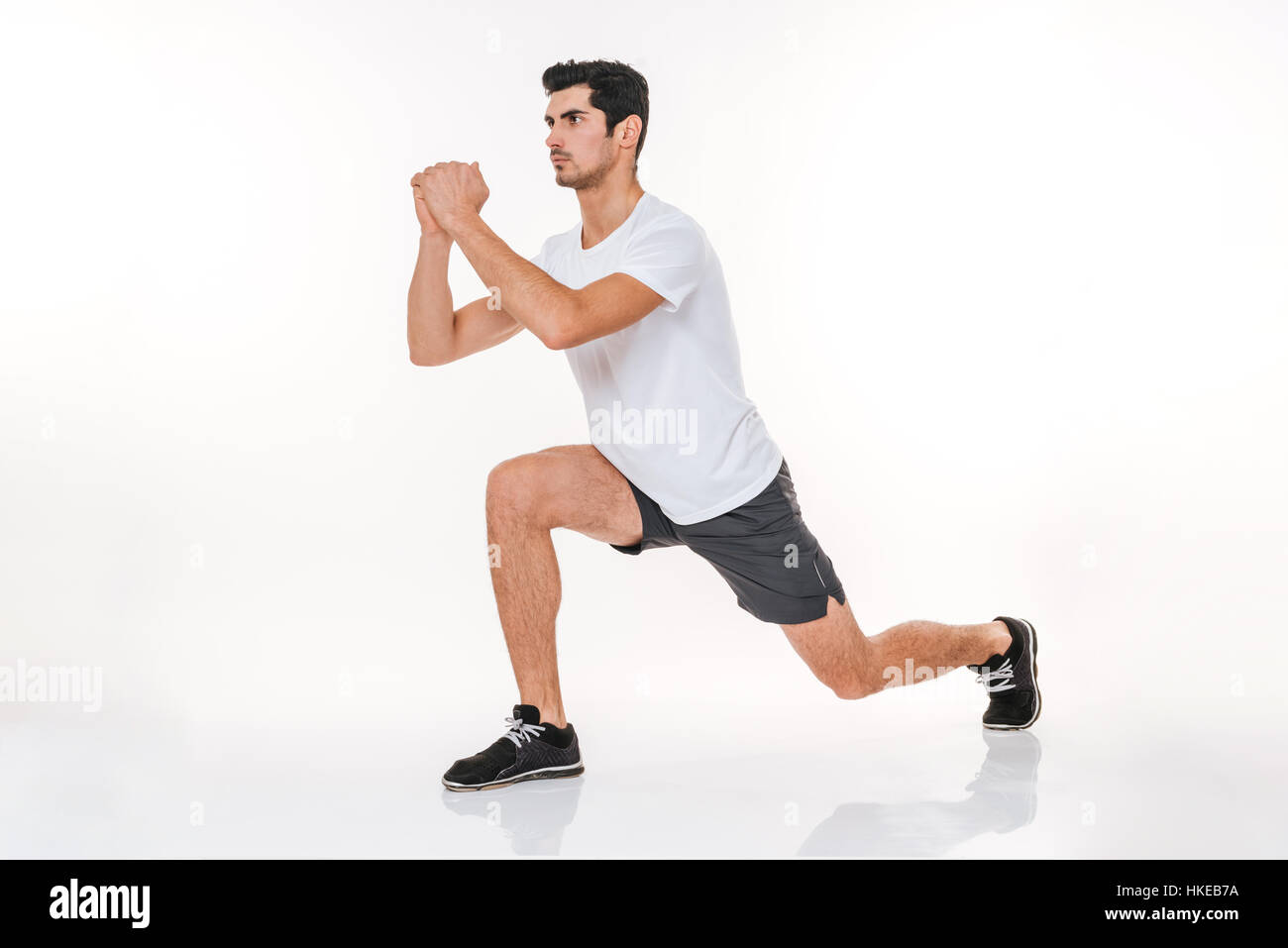 Full length portrait of a fitness man doing squats exercises isolated ...