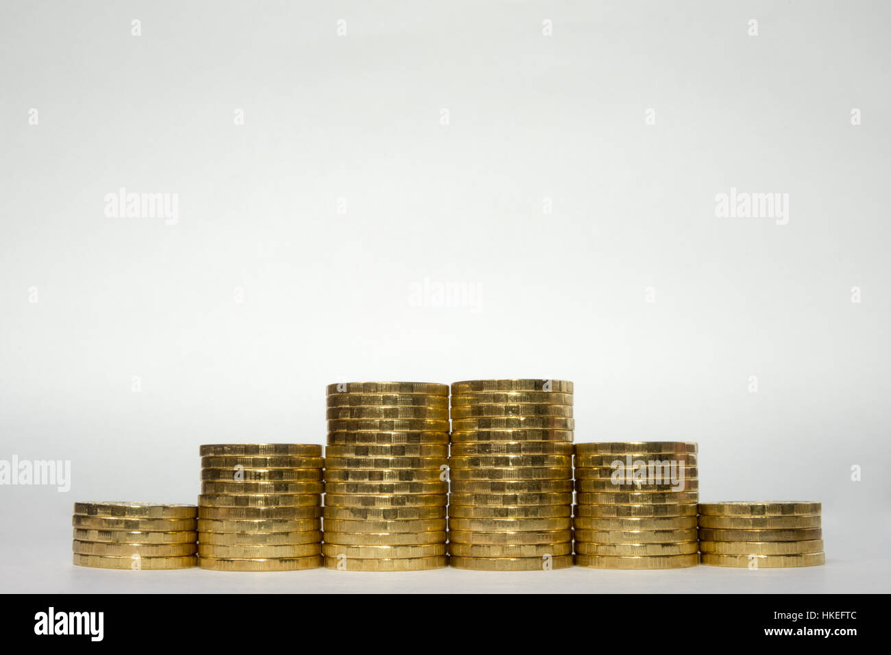 Six stacks of coins increasing height symmetrically on a white ...