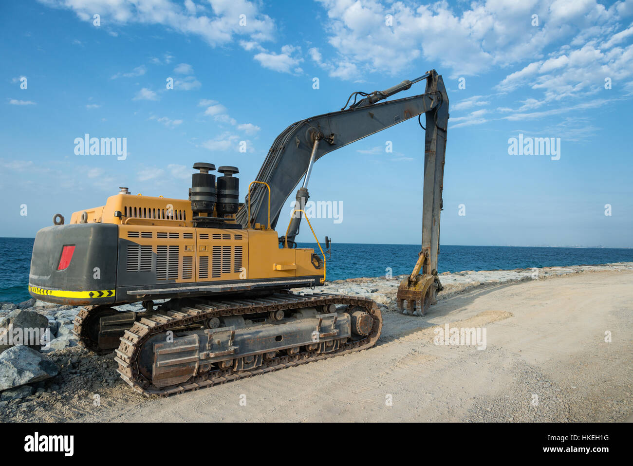 Excavator on rocky embankment on sea shore Stock Photo - Alamy