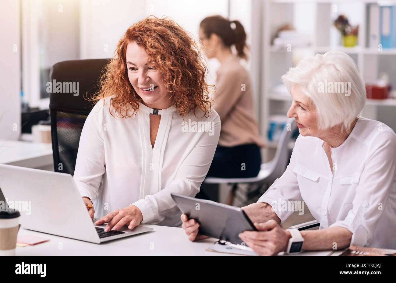 Smiling colleagues using modern gadgets in the office Stock Photo - Alamy