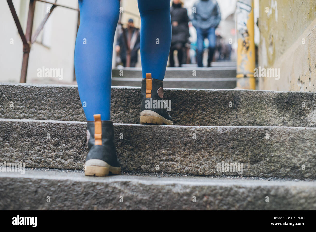 Woman legs in tights and leather boots step upward at outdoor stair ...