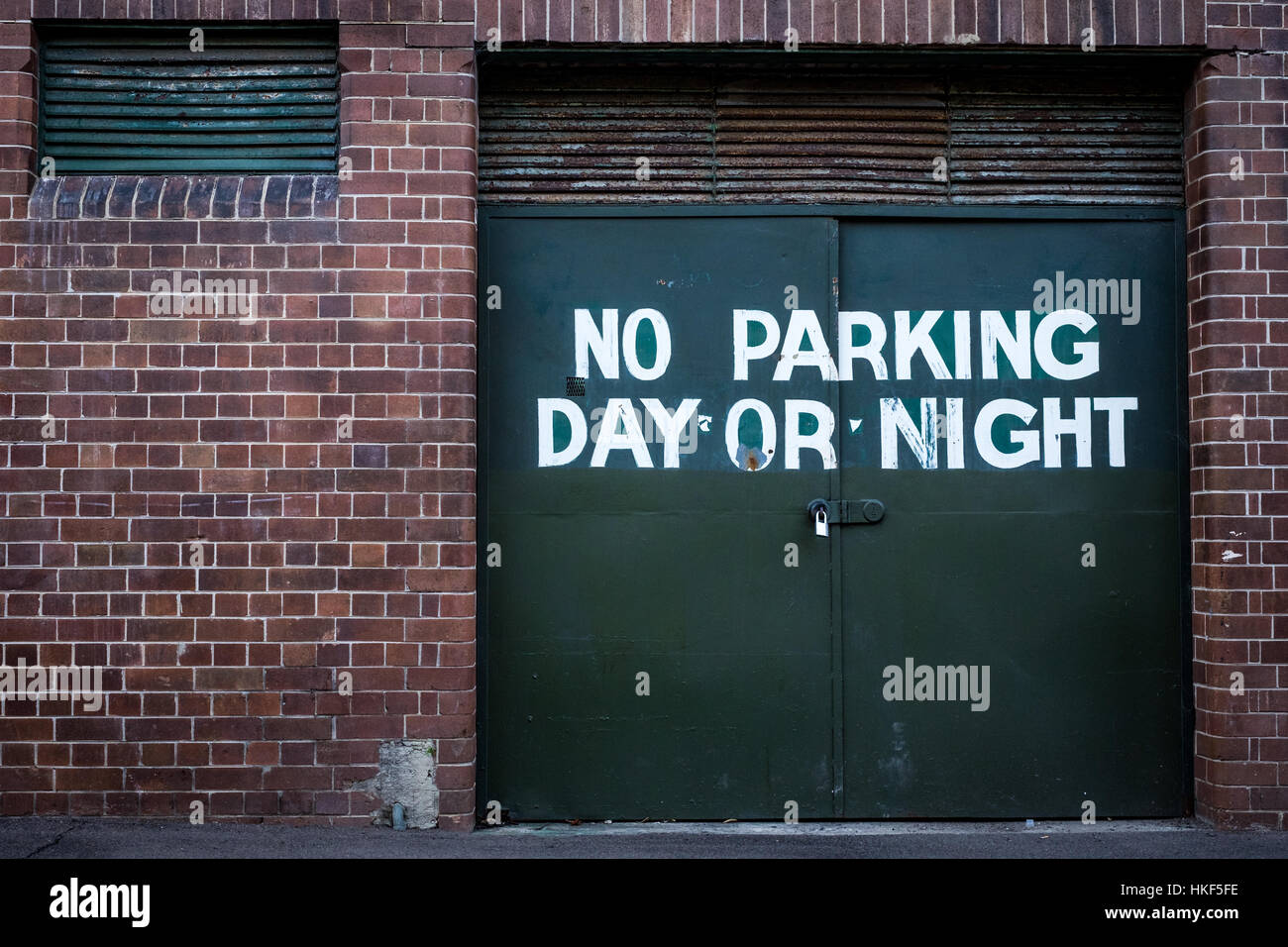 No parking day or night sign painted on green doors of brick building ...