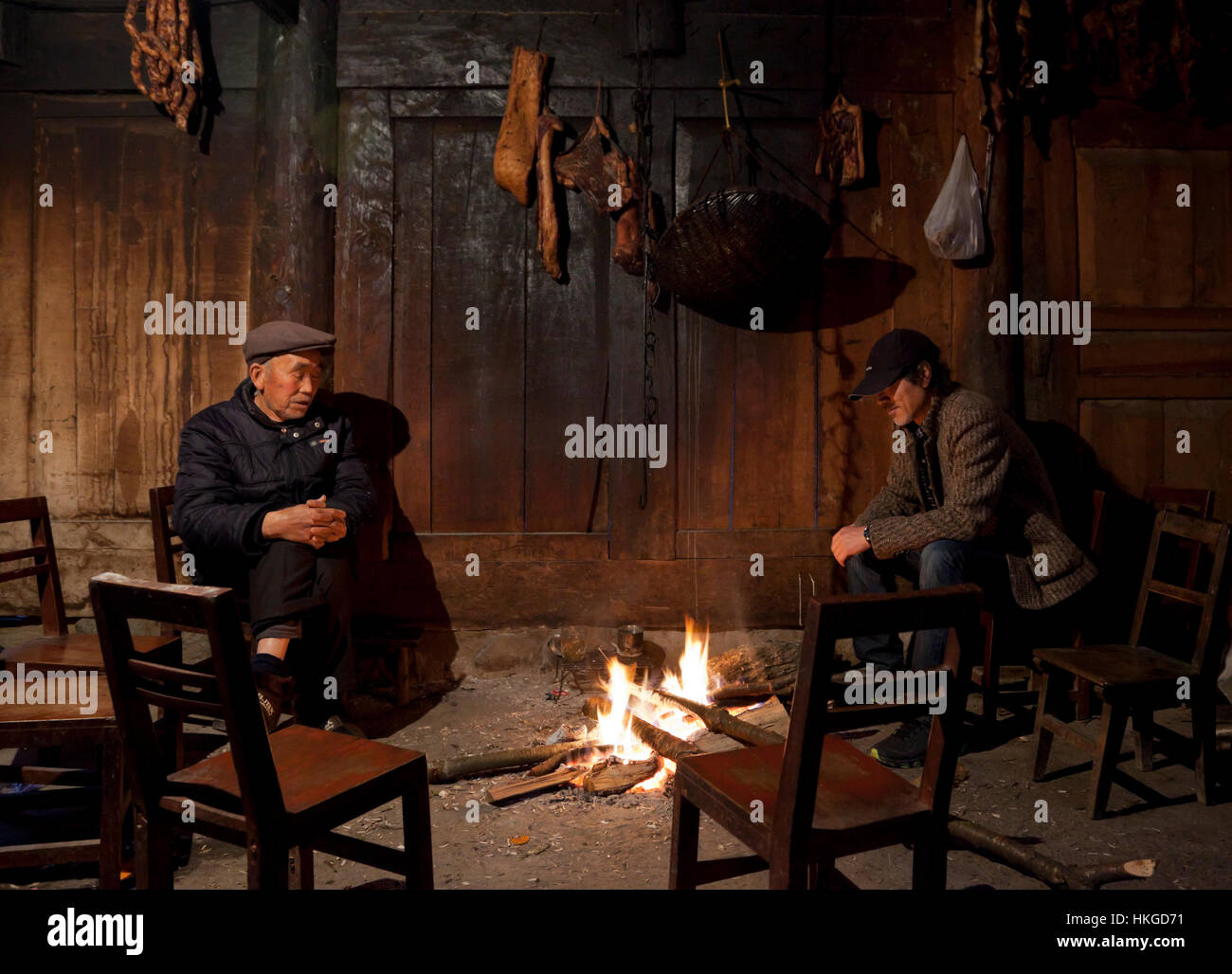 An old man and his nephew sit around the fire in the living room of a ...