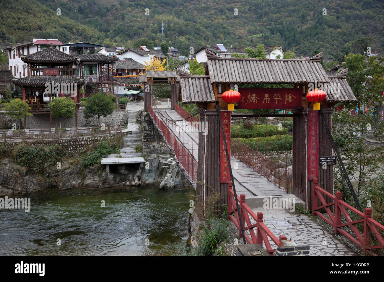 A traditional suspended wooden bridge leads to a village where the old ...