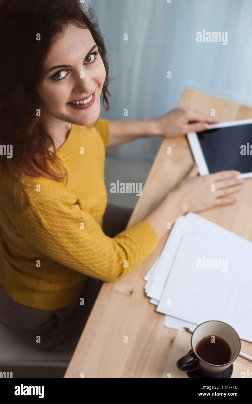 Young caucasian brunette woman taking notes and smiling at camera ...