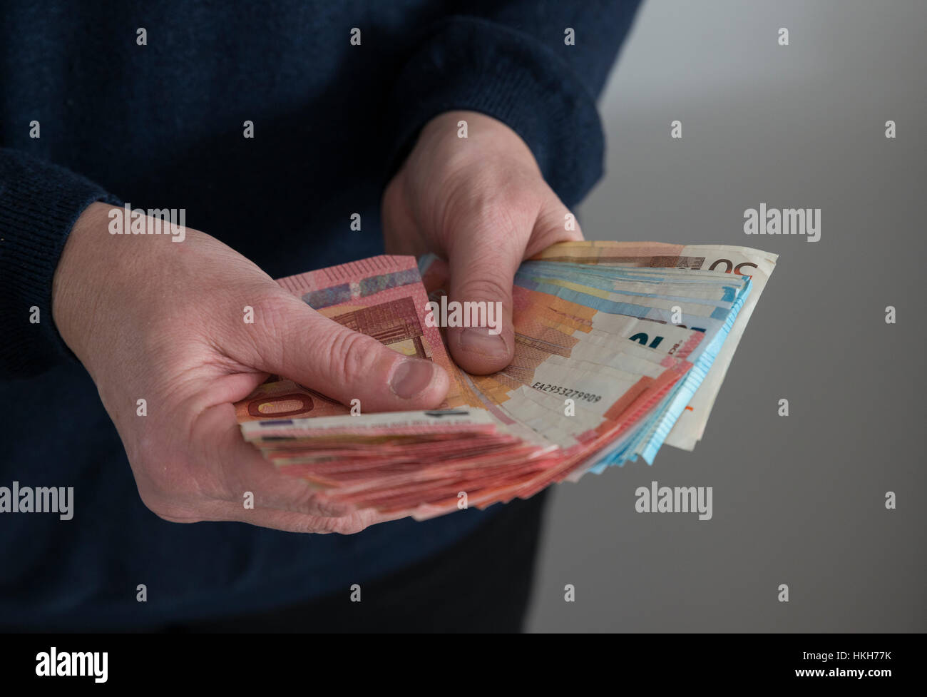 woman counting euro banknotes from ten and twenty with wooden table as ...