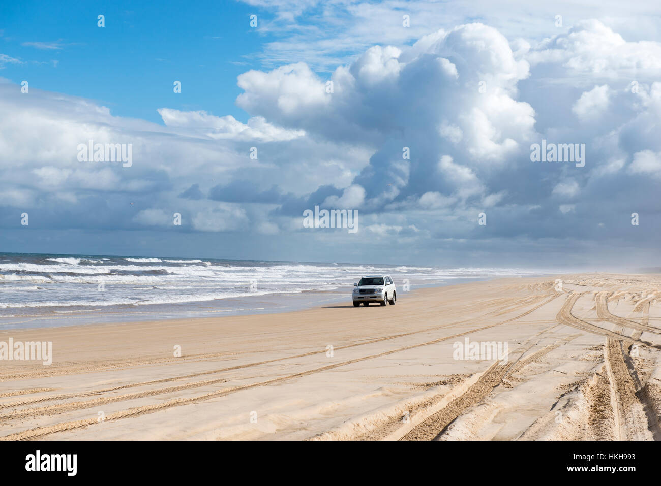 A white 4WD car driving down 75 Mile Beach on Fraser Island, Queensland ...