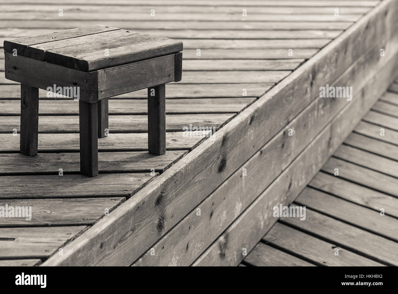A monochrome images of a stool on a wood dock at a cottage in Ontario ...