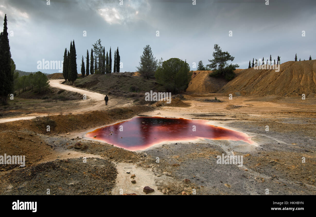Unrecognized man walking near a Lake with red polluted toxic water of ...