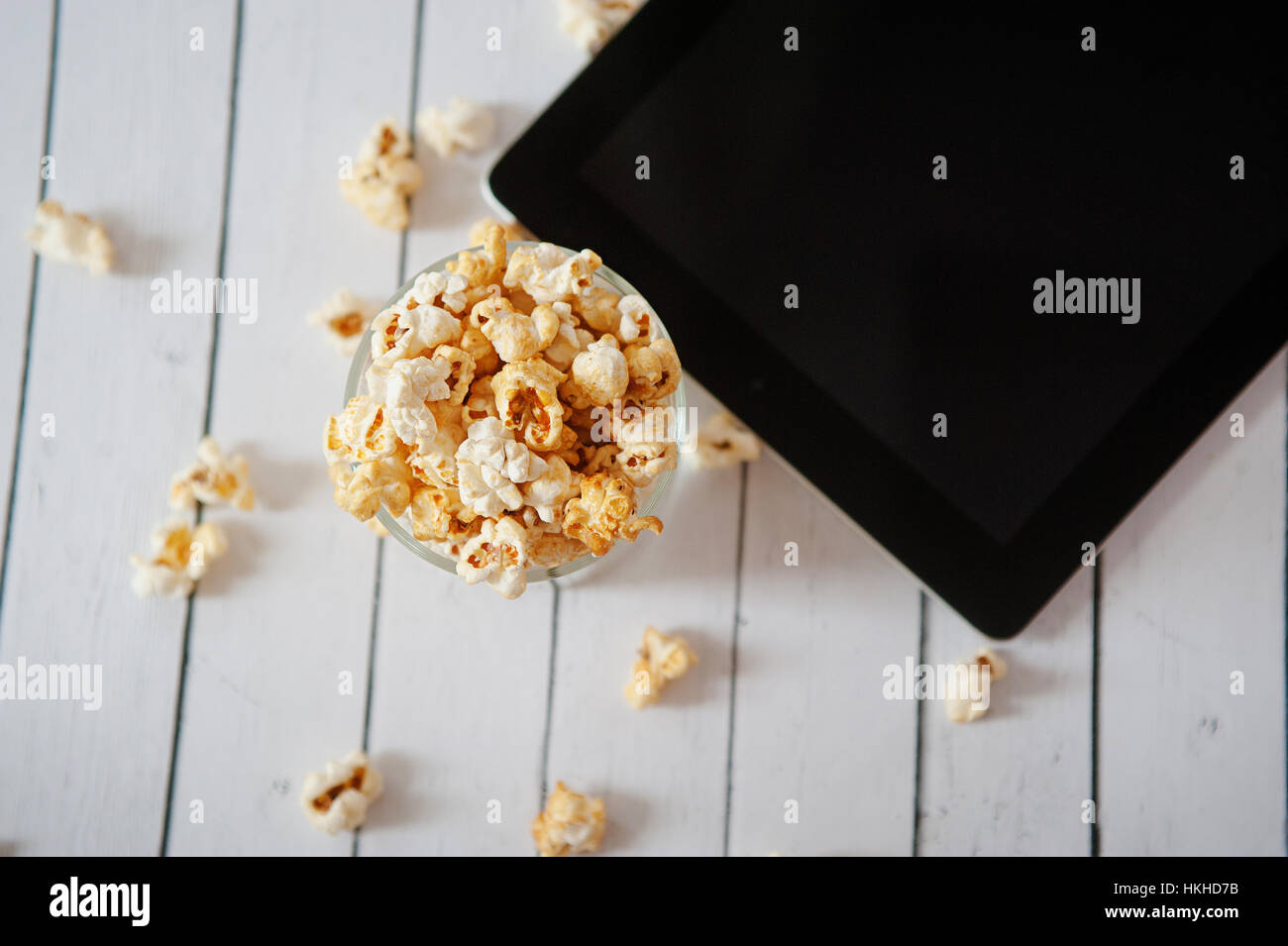 black tablet touch computer gadget with popcorn on white wooden ...