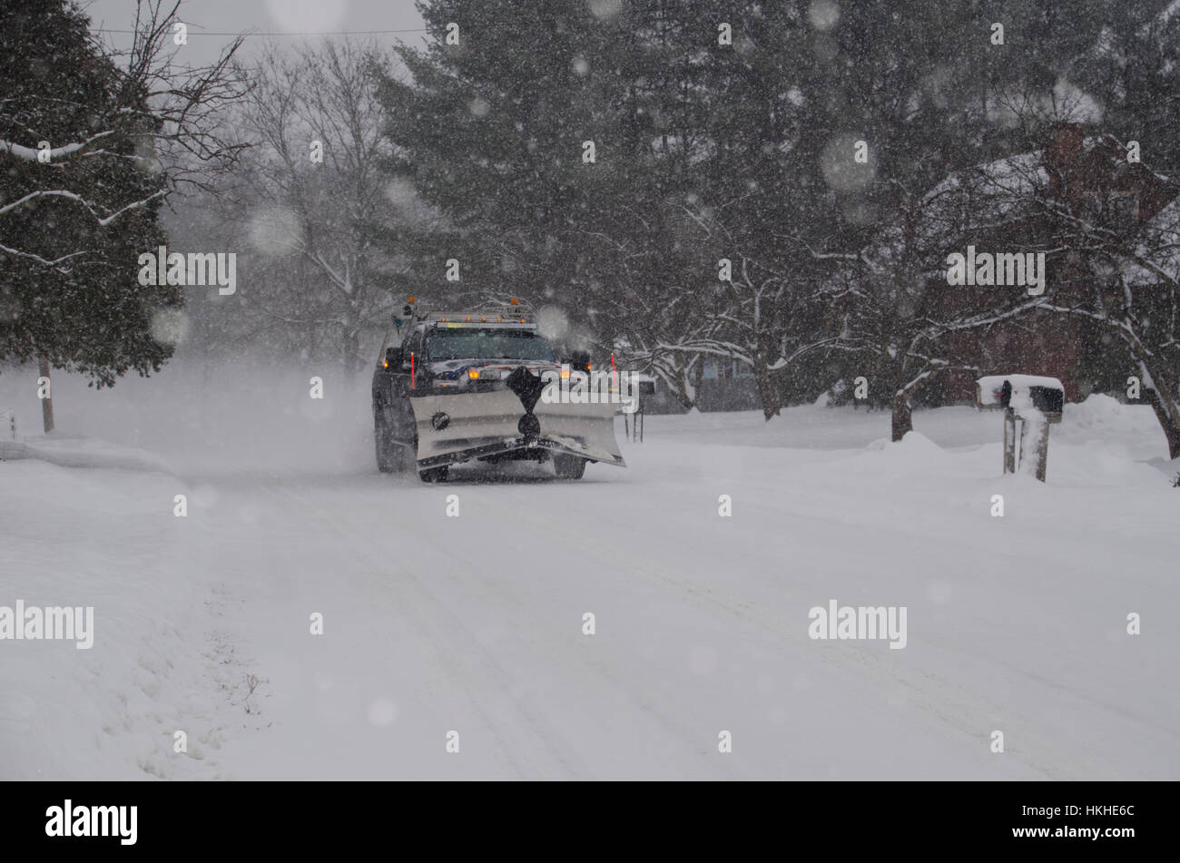Rural road in winter snowstorm with snow plow running to clear roads ...