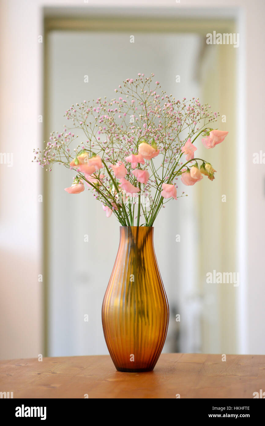 Amber glass fluted vase with flowers in a room Stock Photo - Alamy