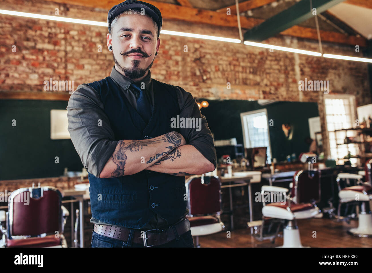 Portrait of handsome young man standing at barber shop. Stylish ...