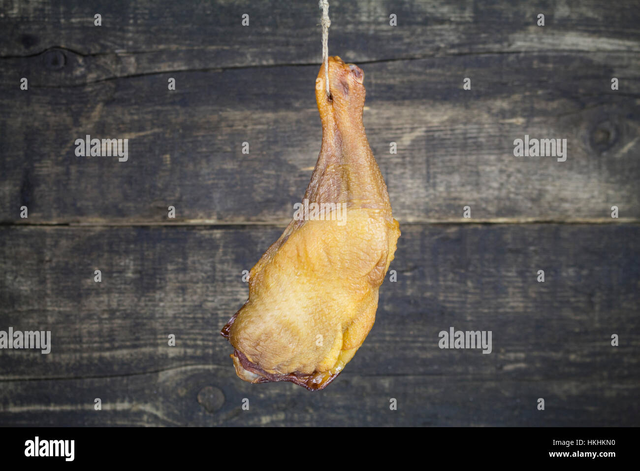 Smoked Chicken Leg Hanging on the Rope Against Wooden Background Stock ...