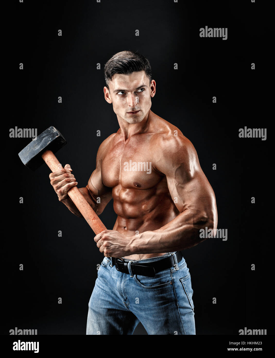 Muscular man with naked torso holding big hummer. Isolated on dark grey ...