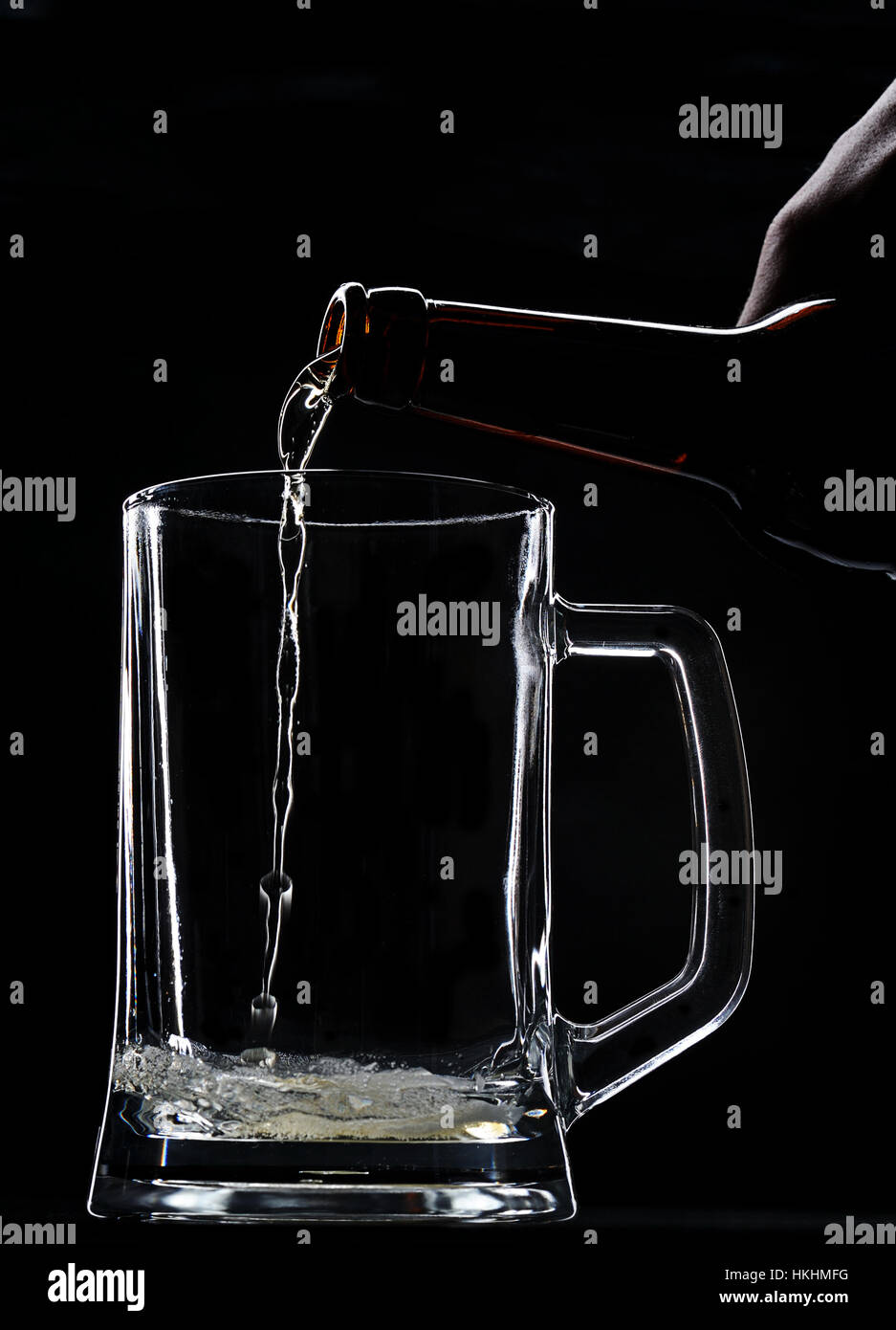 Pouring beer in empty glass from bottle on black background Stock Photo ...