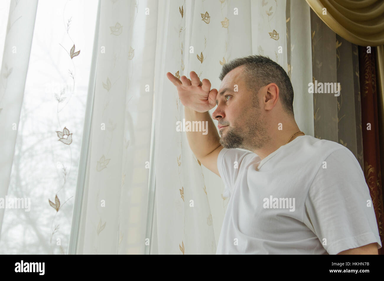 young man looking through a window blind Stock Photo - Alamy
