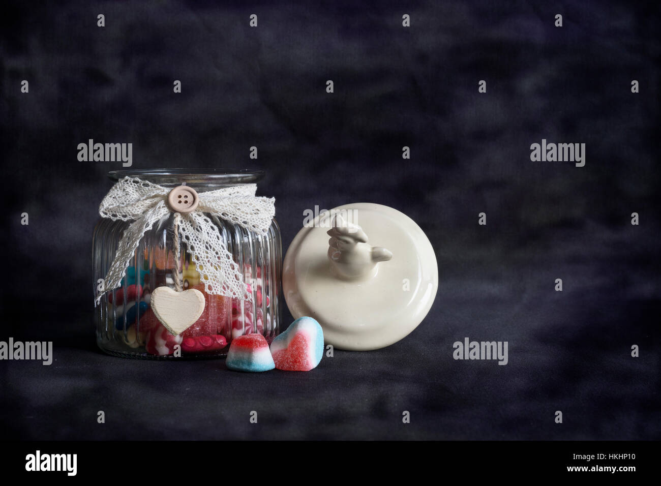 Colorful candies in open glass candy jar decorated with bow ribbon and ...