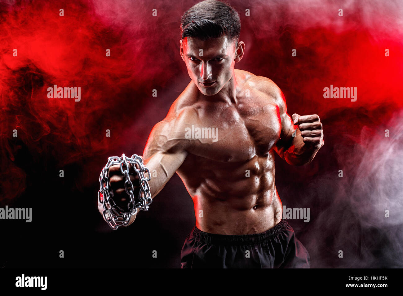 Serious muscular fighter doing the punch with the chains braided over ...