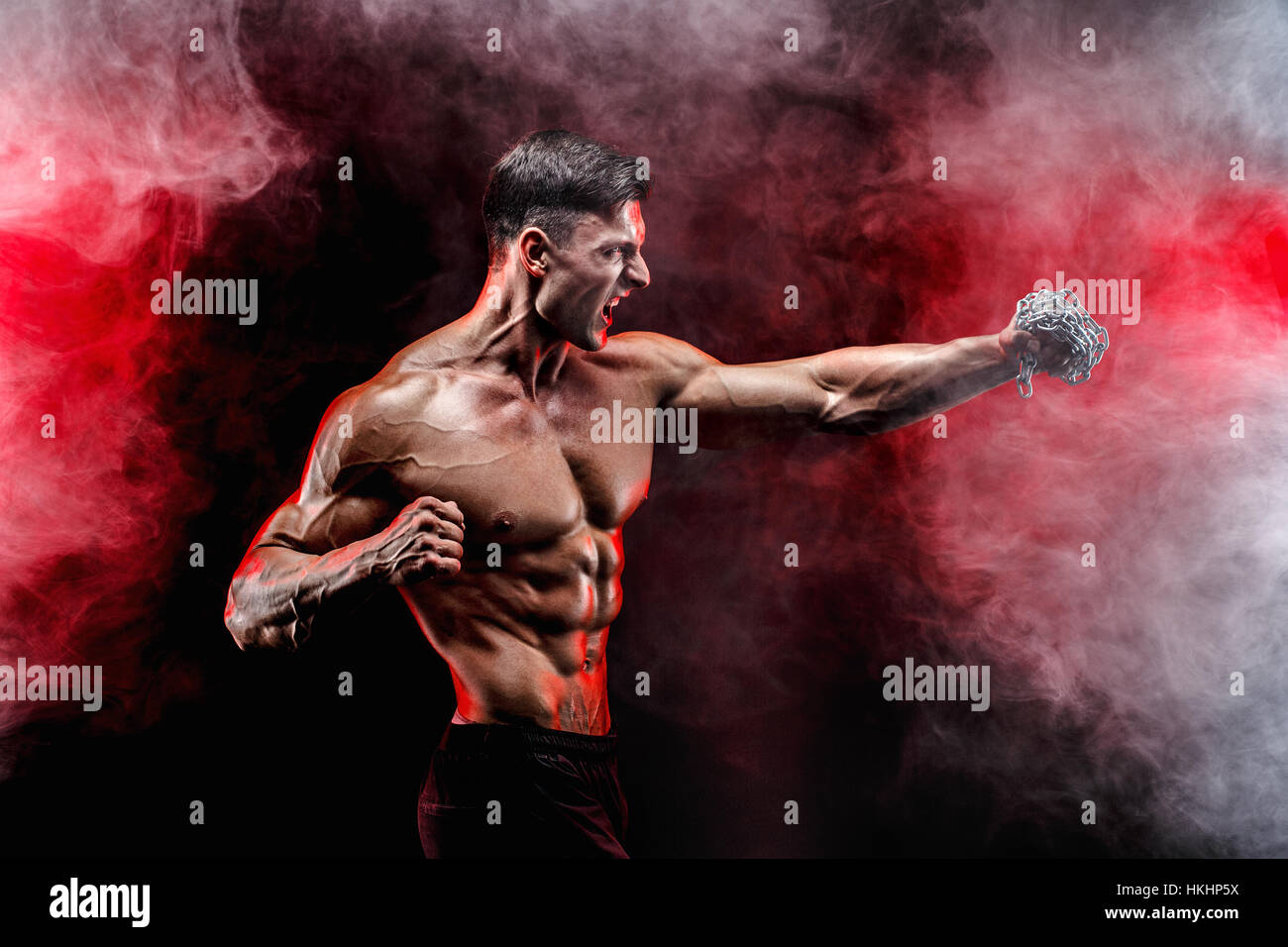 Serious muscular fighter doing the punch with the chains braided over ...