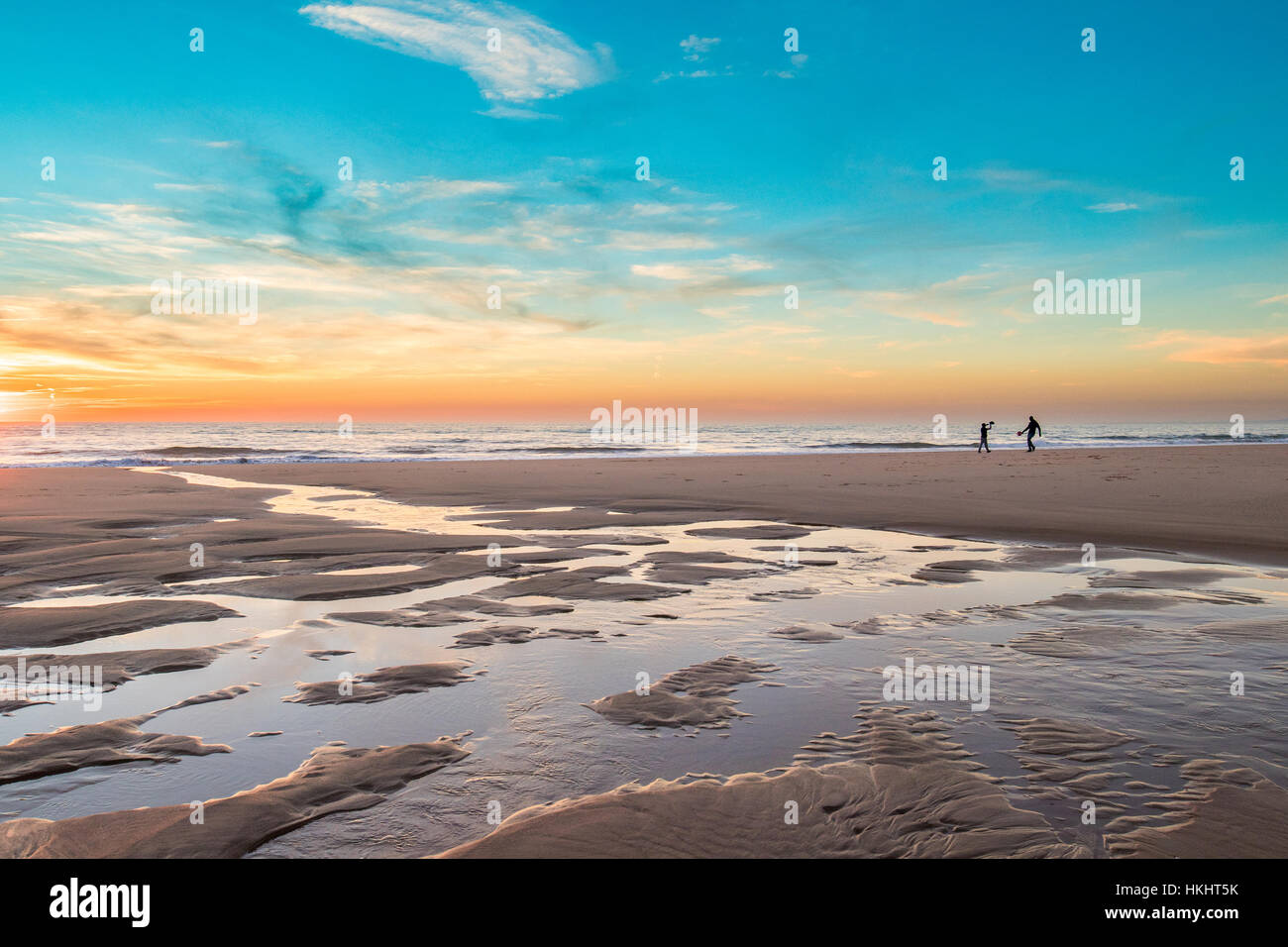 A father and teenager son playing racket in the beach during a winter ...