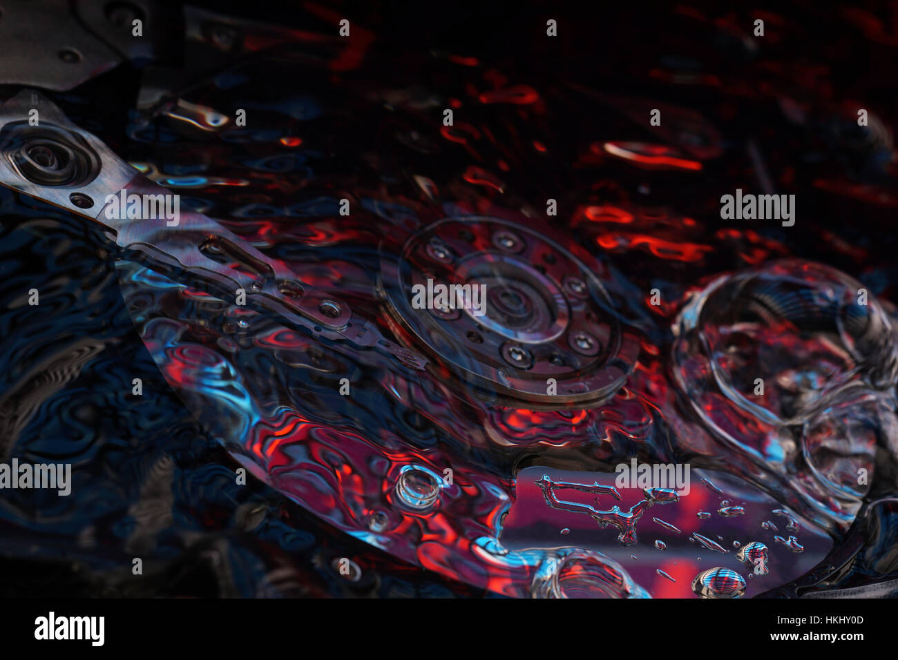 Opened Computer hard disk drive in studio with bubbles and dark red and ...