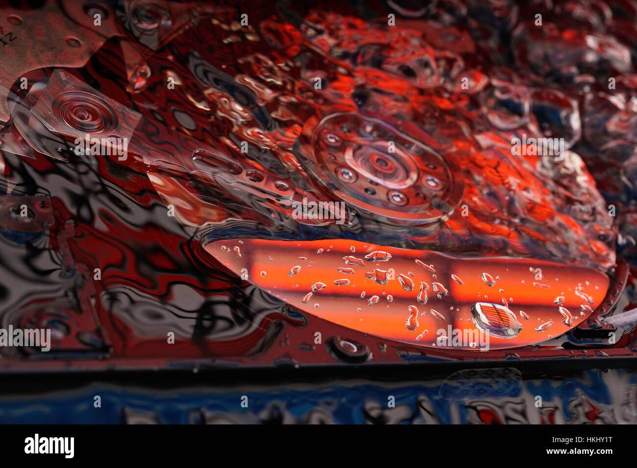 Opened Computer hard disk drive in studio with bubbles and dark red and ...