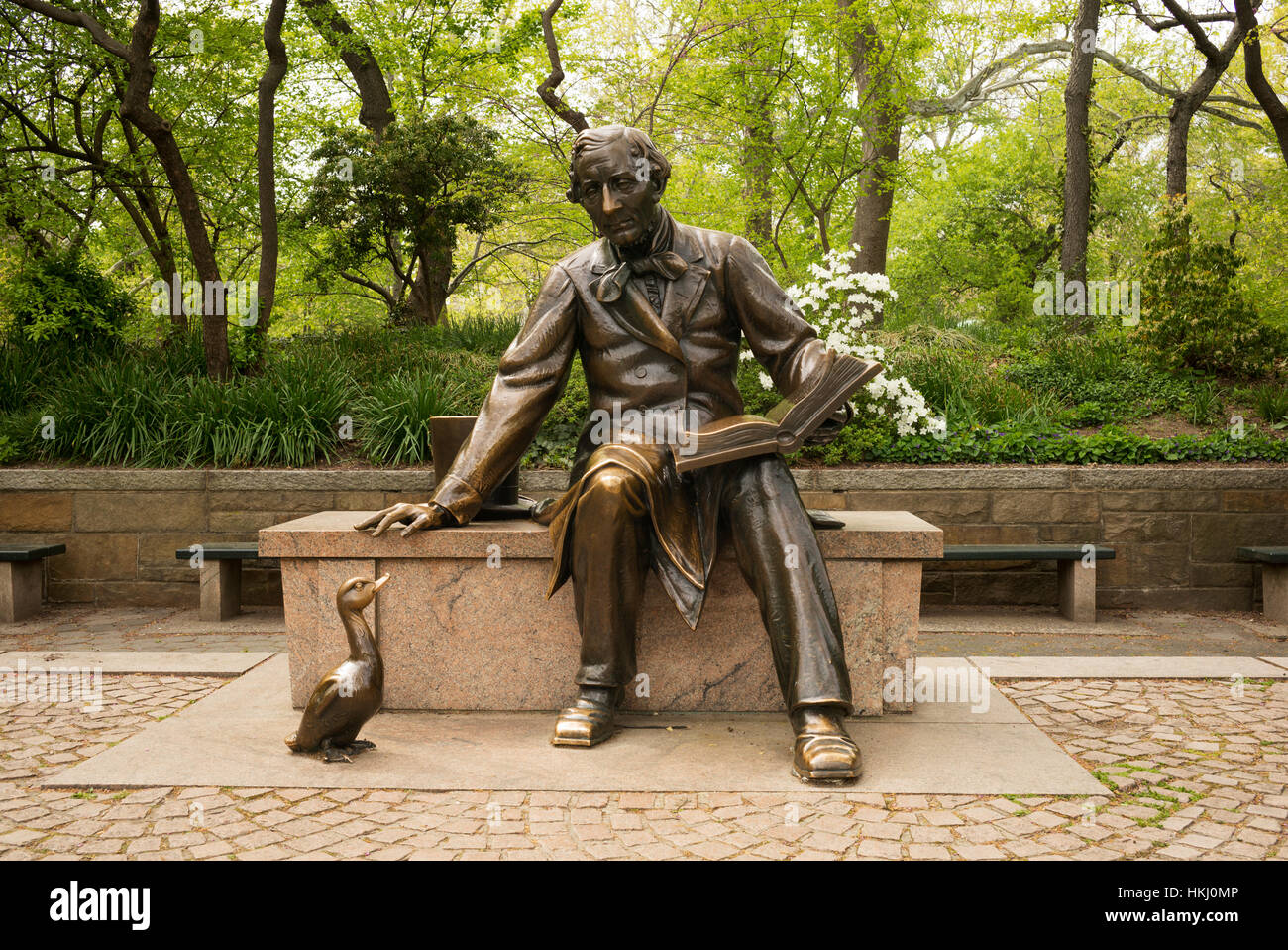 Statue of Hans Christian Anderson sitting on a bench reading a book in ...