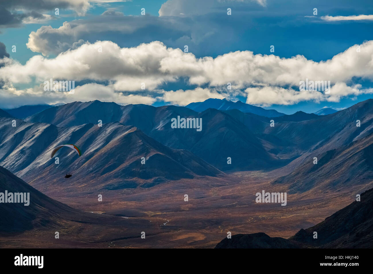 Man paragliding over the mountain of the Tombstone Range along the ...