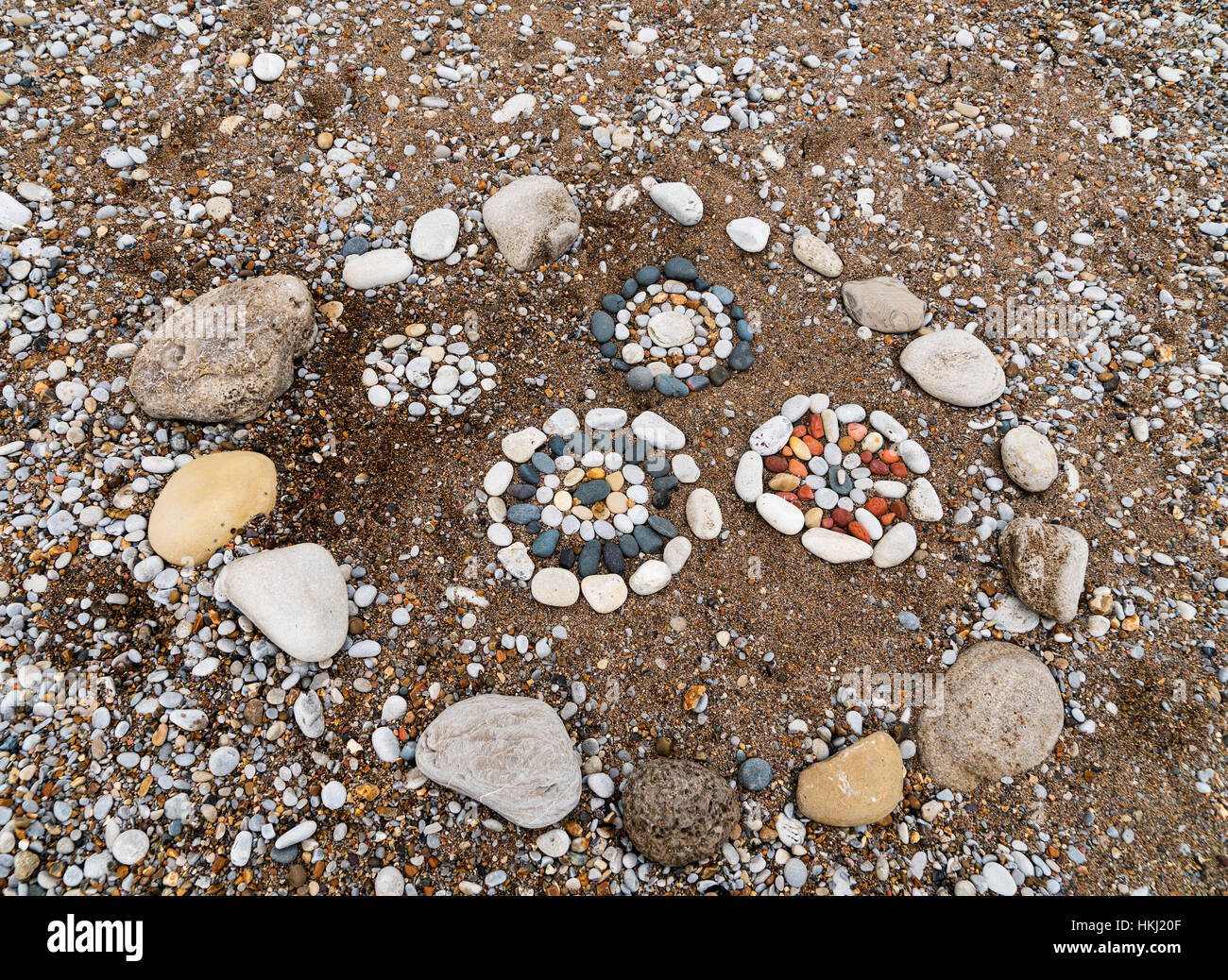 Designs made with various coloured rocks in the sand on the beach ...