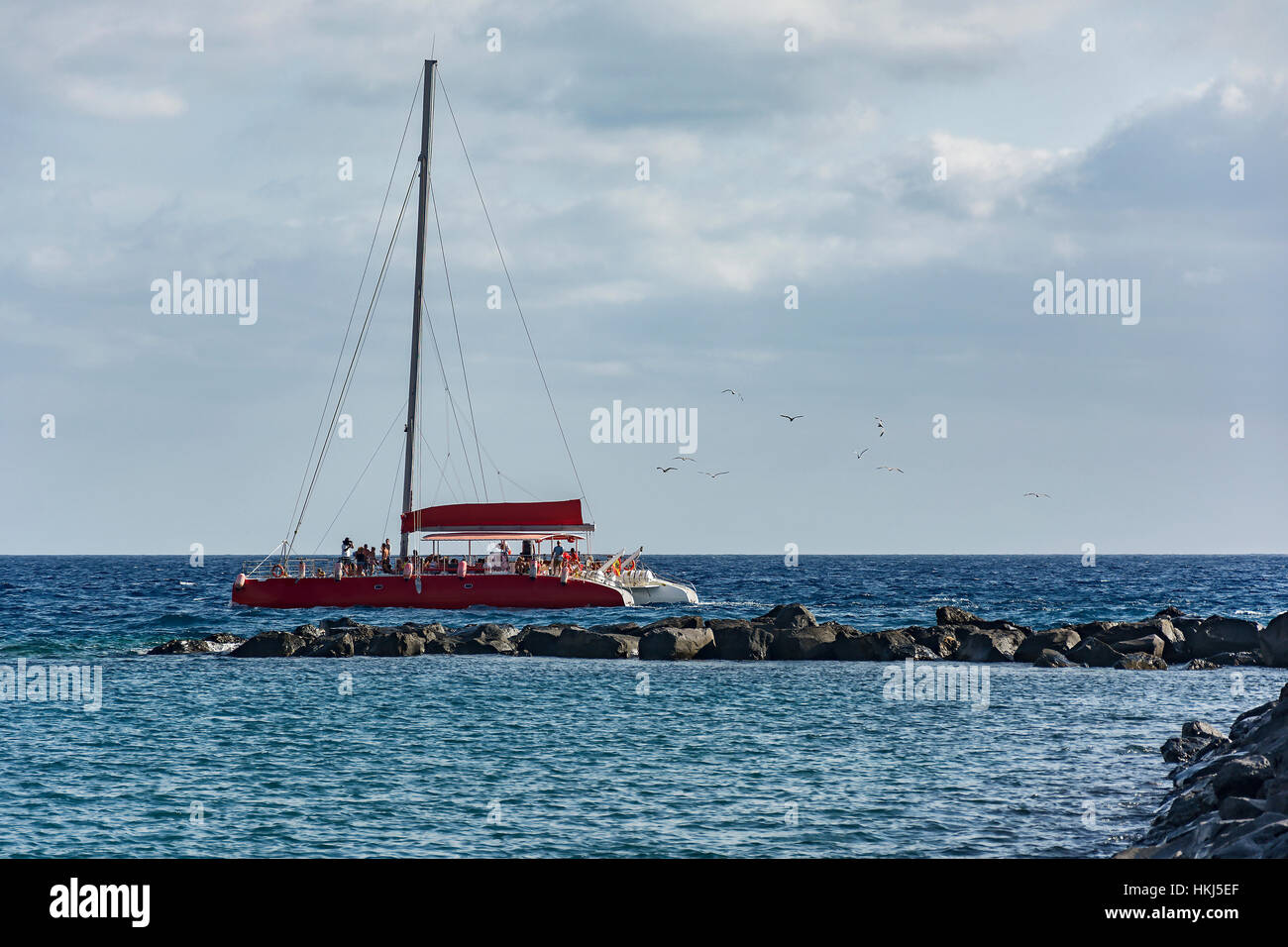 Red catamaran sailing with passengers floating in the sea along the ...
