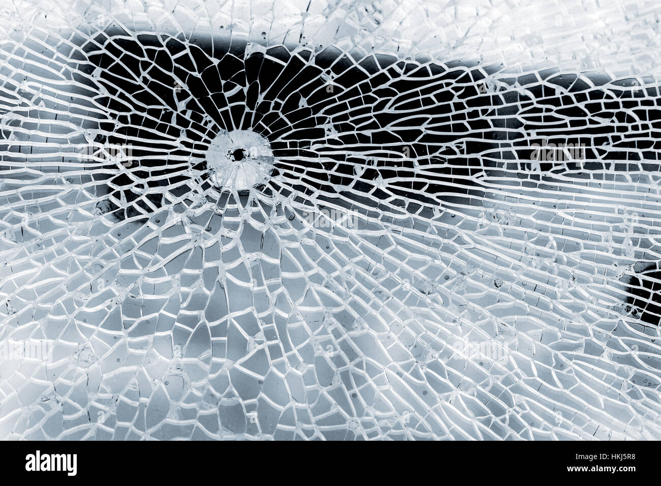 Broken strained glass with bullet hole and craks. Close-up background ...