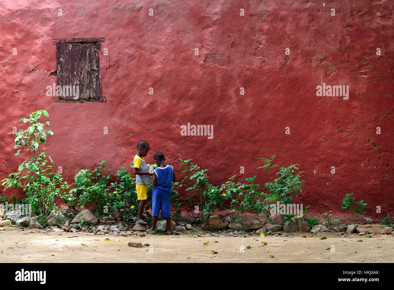 Two children in front of a red house facade, Île de Gorée, Dakar ...