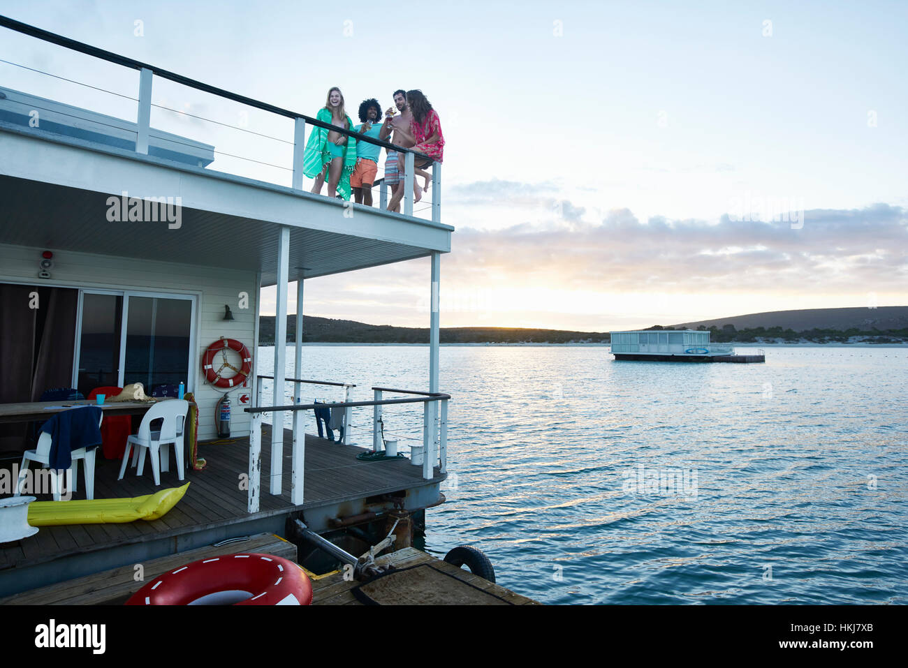 Young adult friends hanging out on deck of summer houseboat on ocean ...