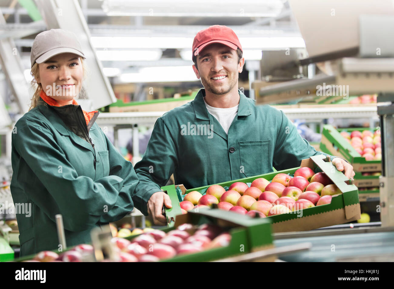 Portrait smiling workers with boxes of red apples in food processing ...