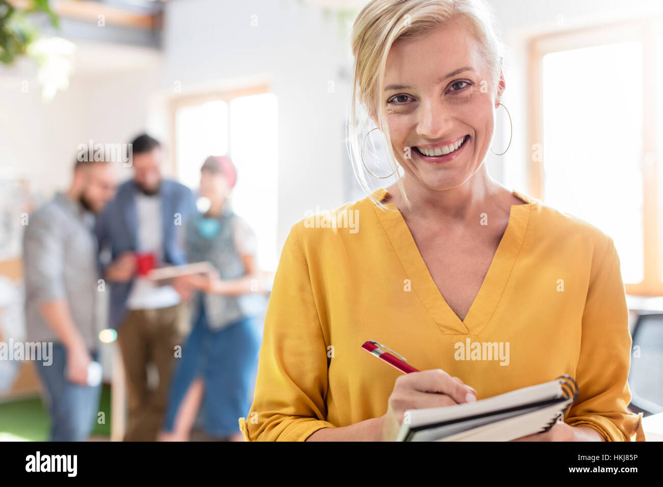 Portrait smiling female design professional taking notes in notebook in ...