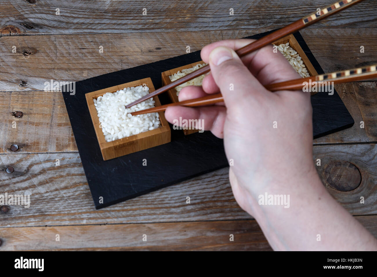 Man's hand picking rice with chopsticks from wooden bowls Stock Photo ...