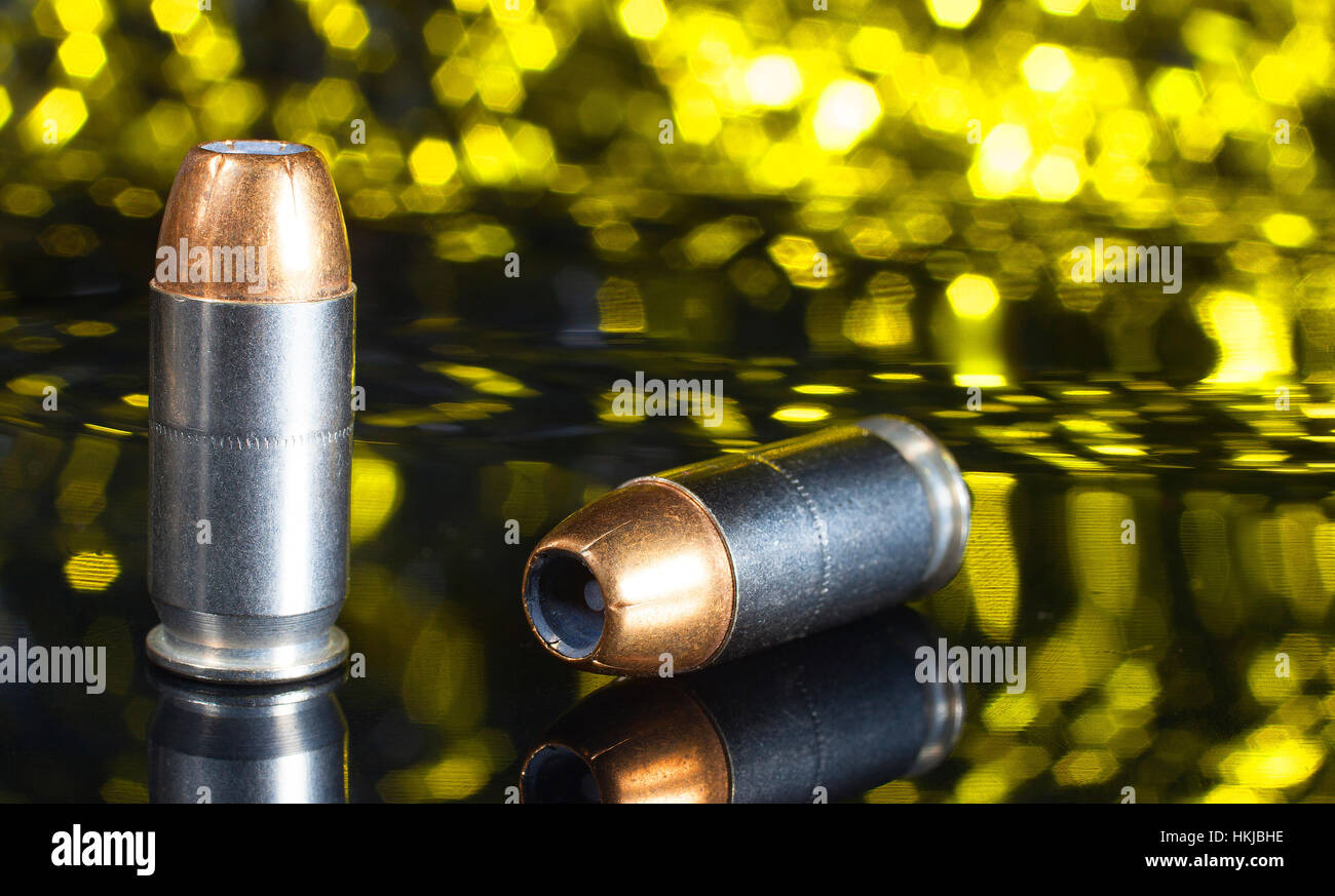 Two handgun cartridges with hollow point bullets and a yellow ...