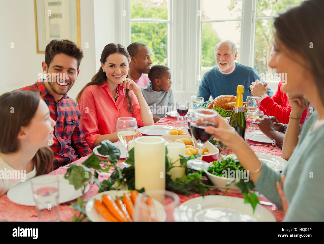 Multi-ethnic multi-generation family enjoying Christmas dinner at table ...