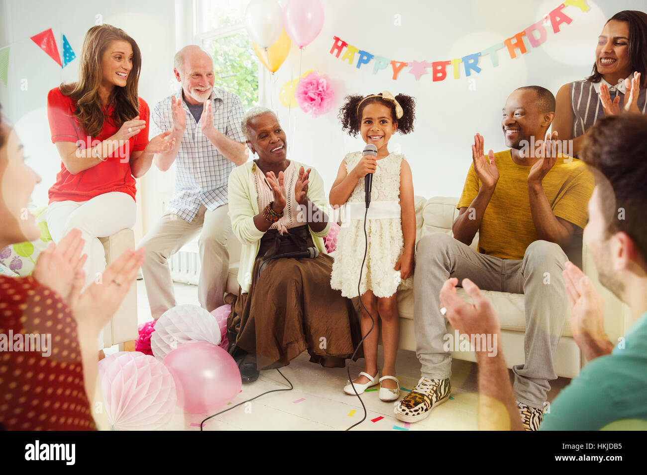 Multi-ethnic family clapping for girl singing karaoke with microphone ...