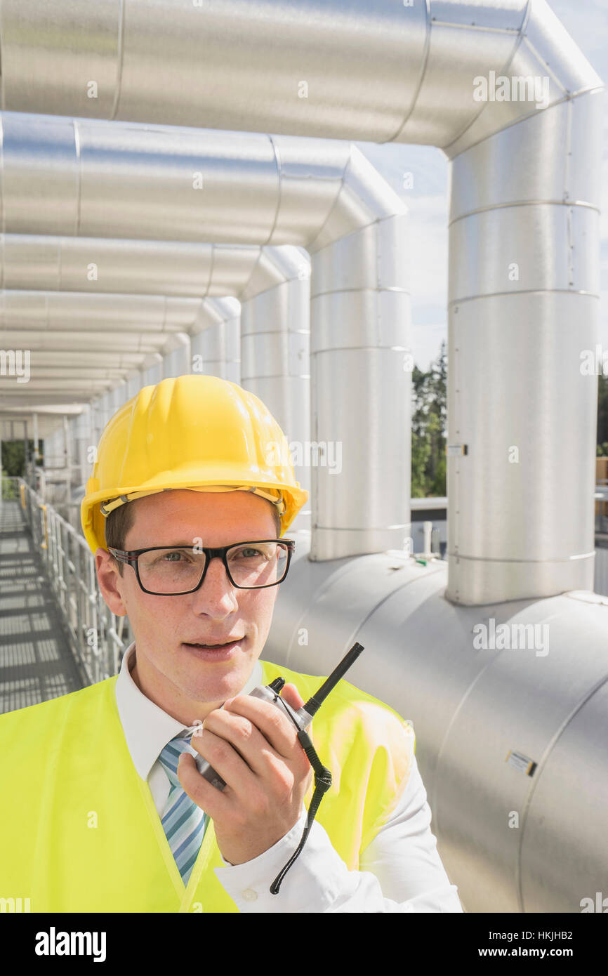 Young engineer talking with walkie-talkie at geothermal power station ...