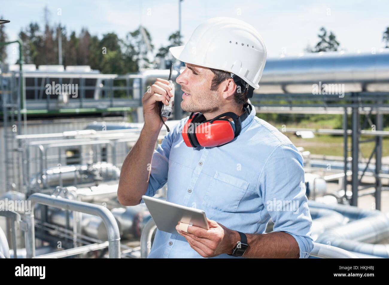 Male engineer talking with walkie-talkie at geothermal power station ...