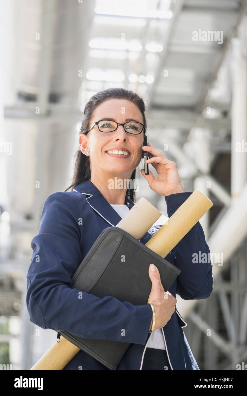 Female engineer talking on mobile phone at geothermal power station ...