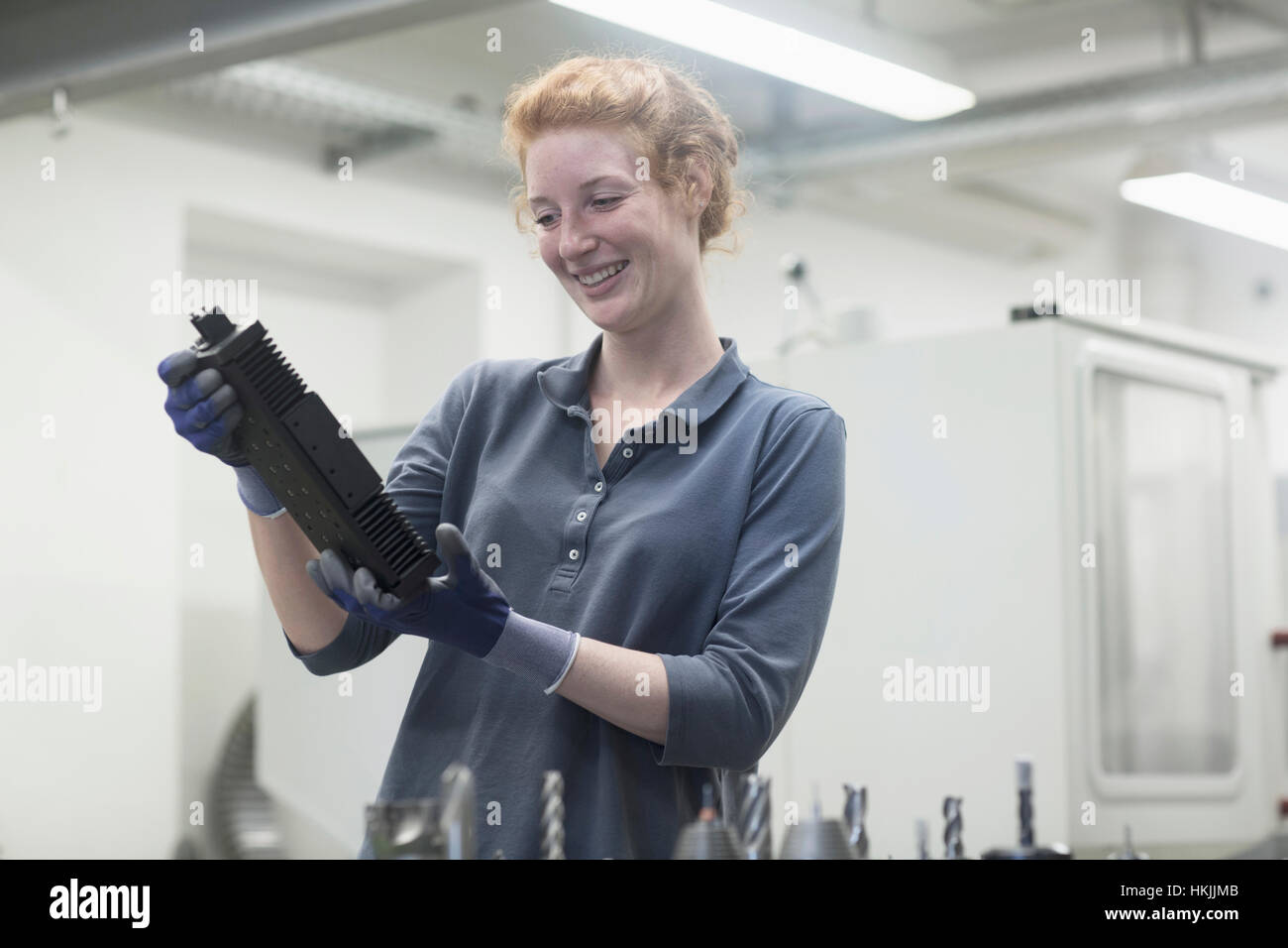Young female engineer looking at machine part in an industrial plant ...
