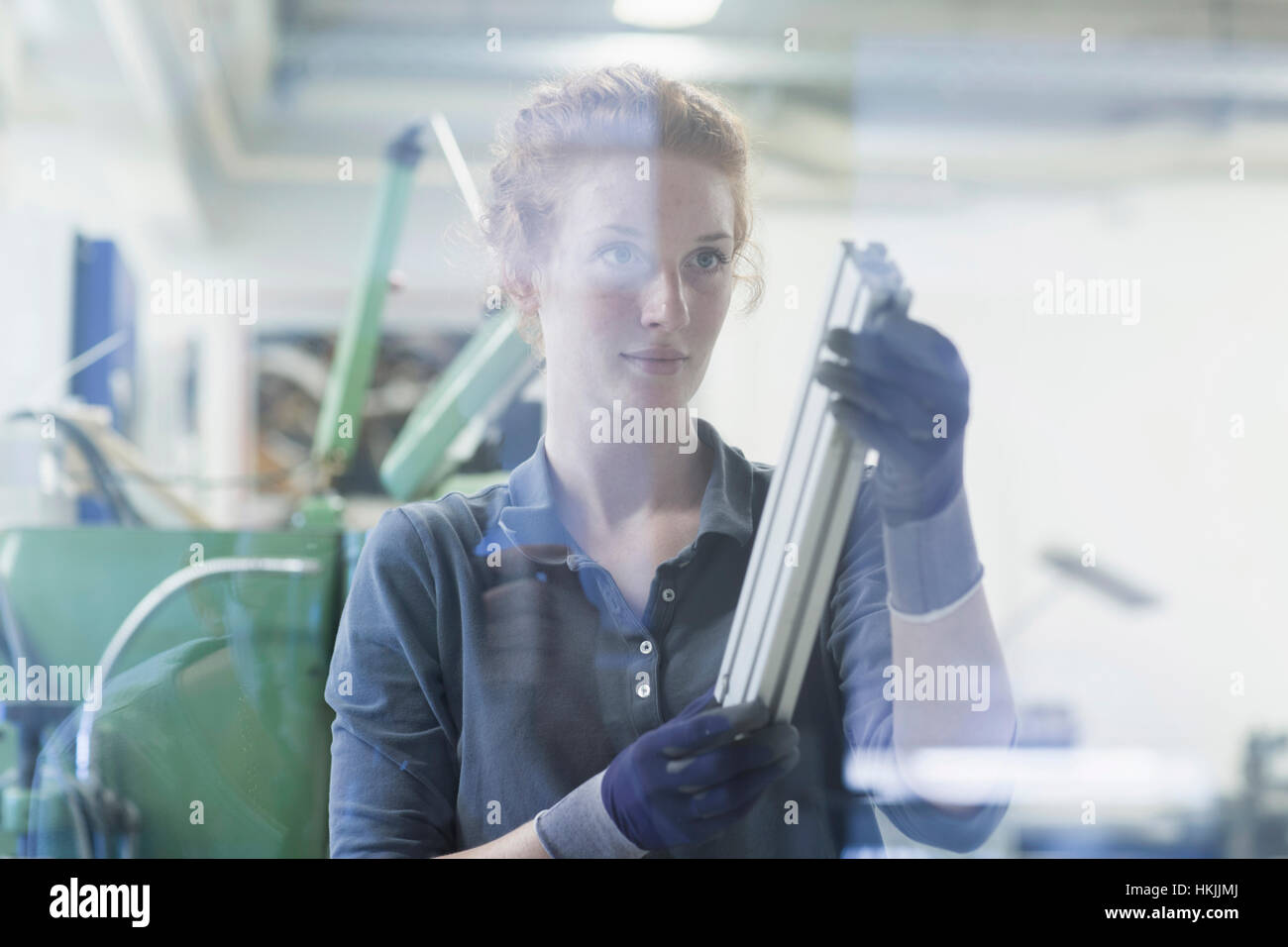 Young female engineer looking at machine part in an industrial plant ...