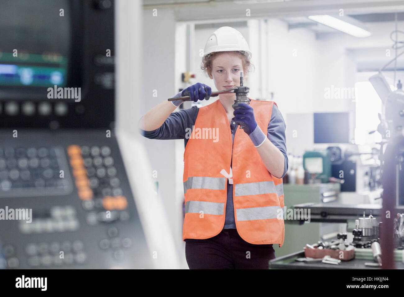 Young female engineer repairing machine part in an industrial plant ...