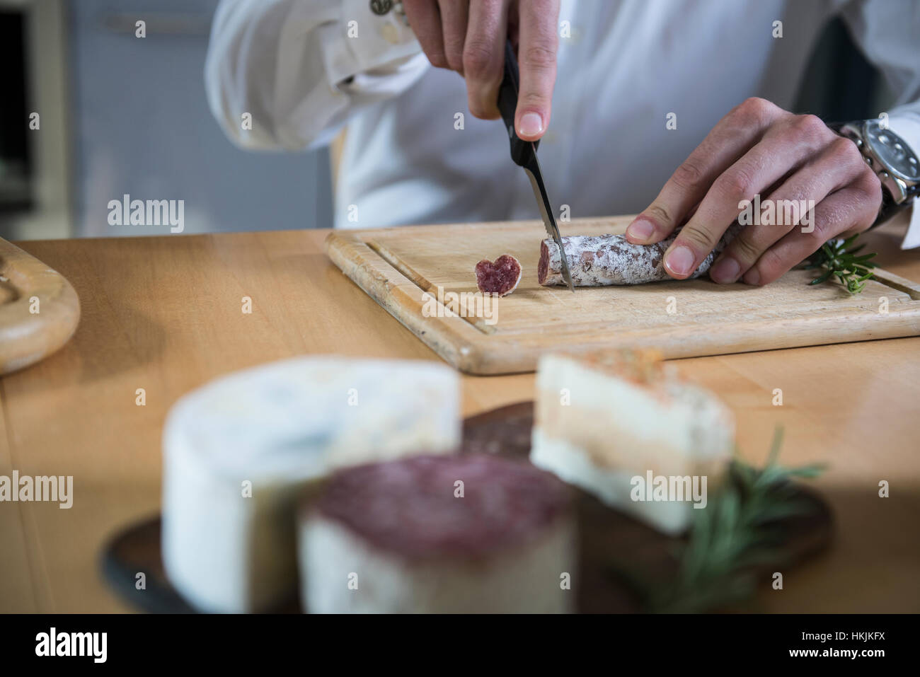 Mid section of a man cutting salami in the kitchen, Bavaria, Germany ...