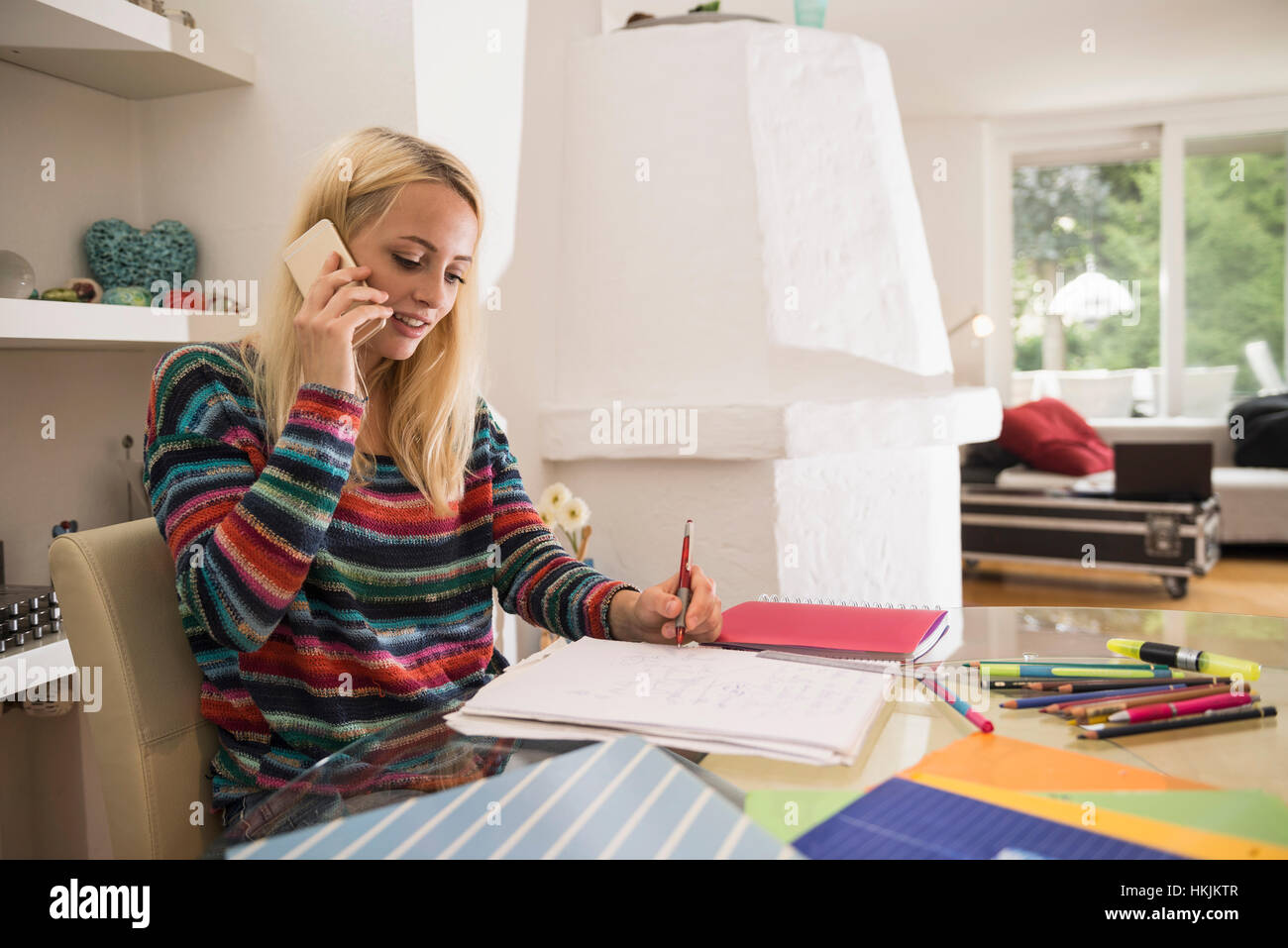 Young student doing homework with mobile phone in the living room ...